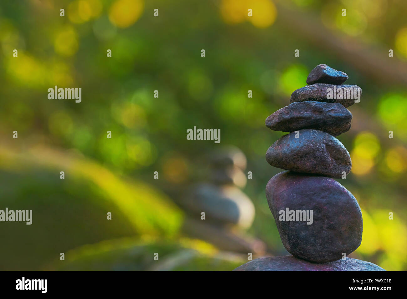 Stacked stone pyramid in front of green blurry background with bokeh ...