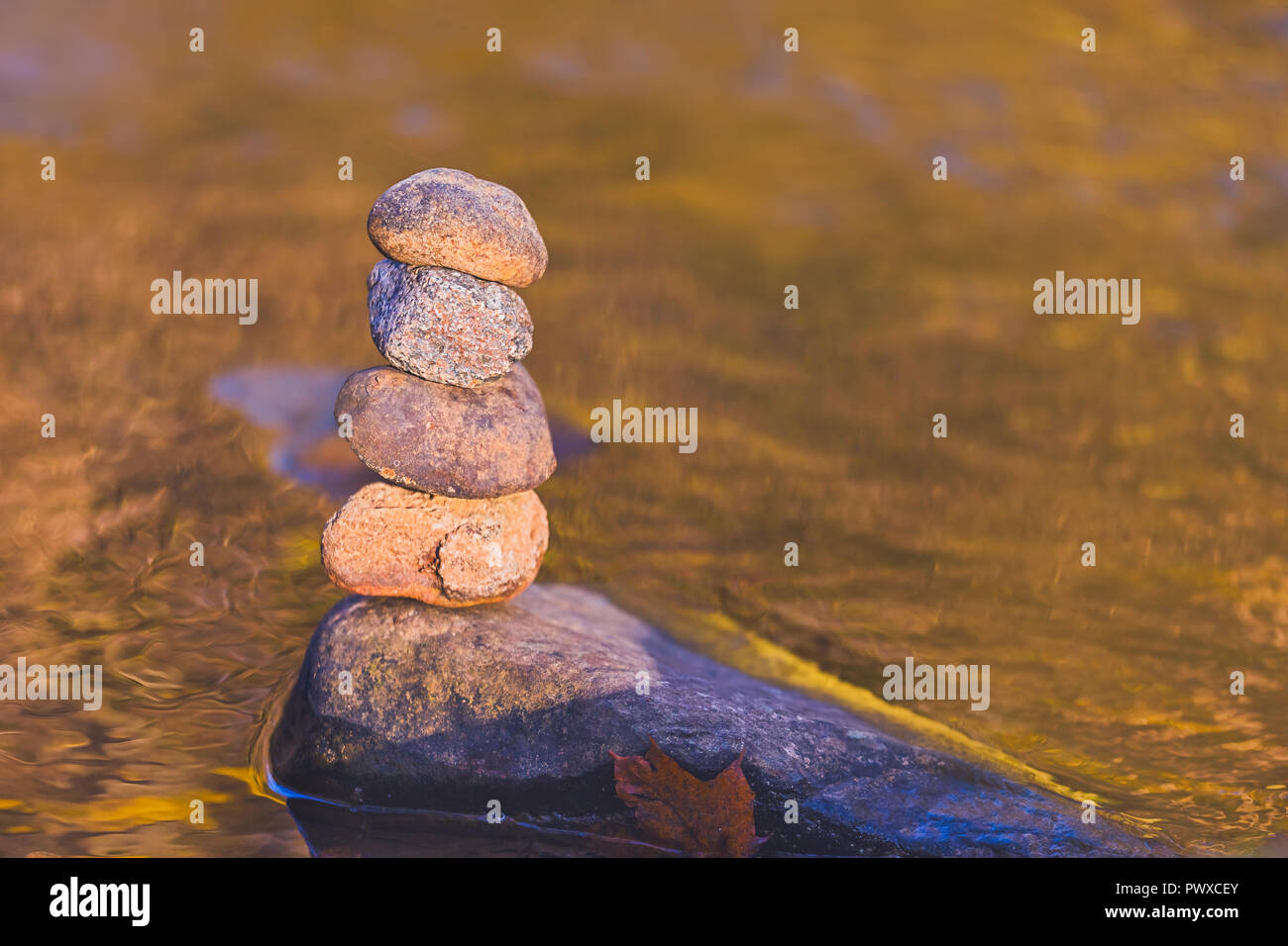 Stacked stone pyramid in front of yellow blurry background with bokeh ...