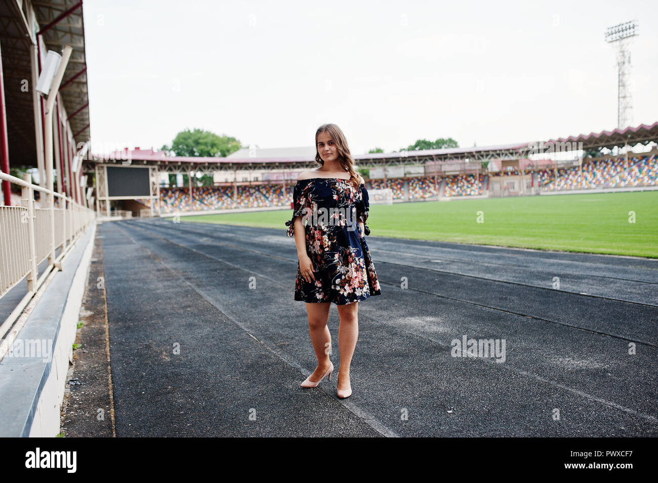 Portrait of a fabulous girl in dress and high heels on the track at the ...