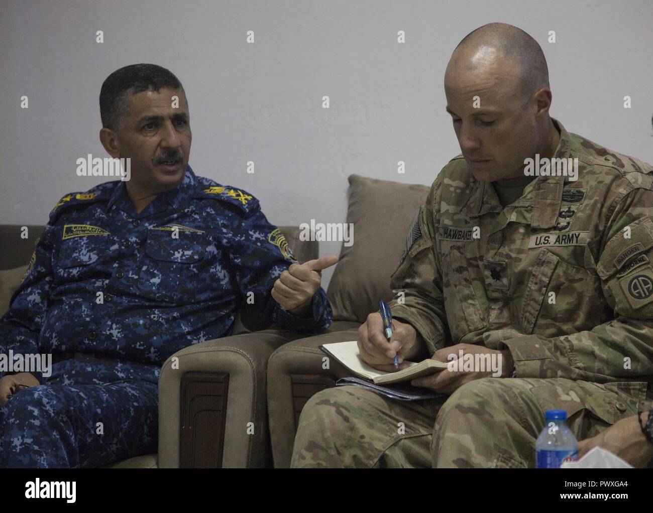An Iraqi federal police member speaks with U.S. Army Lt. Col. John ...