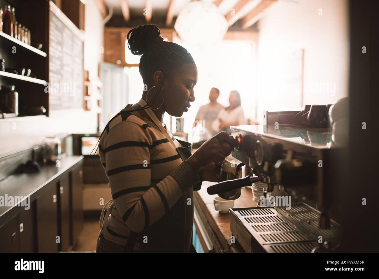 Young African barista frothing milk behind a cafe counter Stock Photo ...