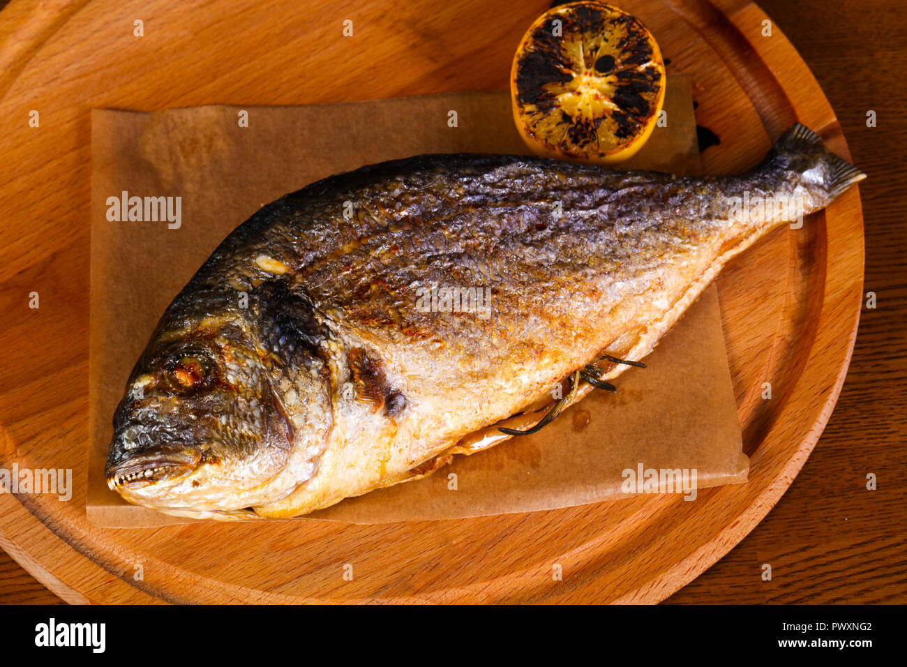 Grilled dorada with lemon over wooden background Stock Photo - Alamy
