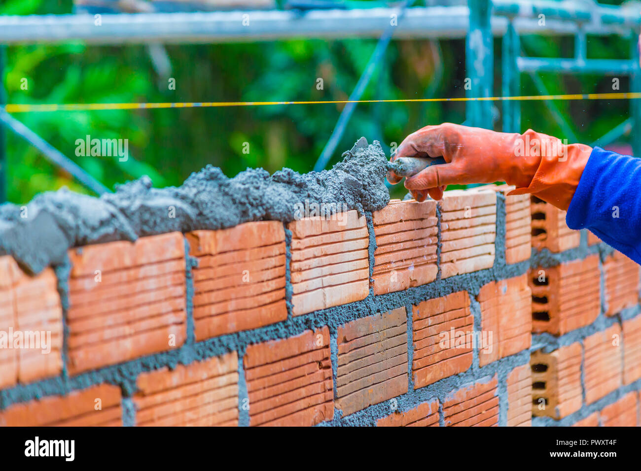 Hand of construction worker putting down mortar paste on top of ...