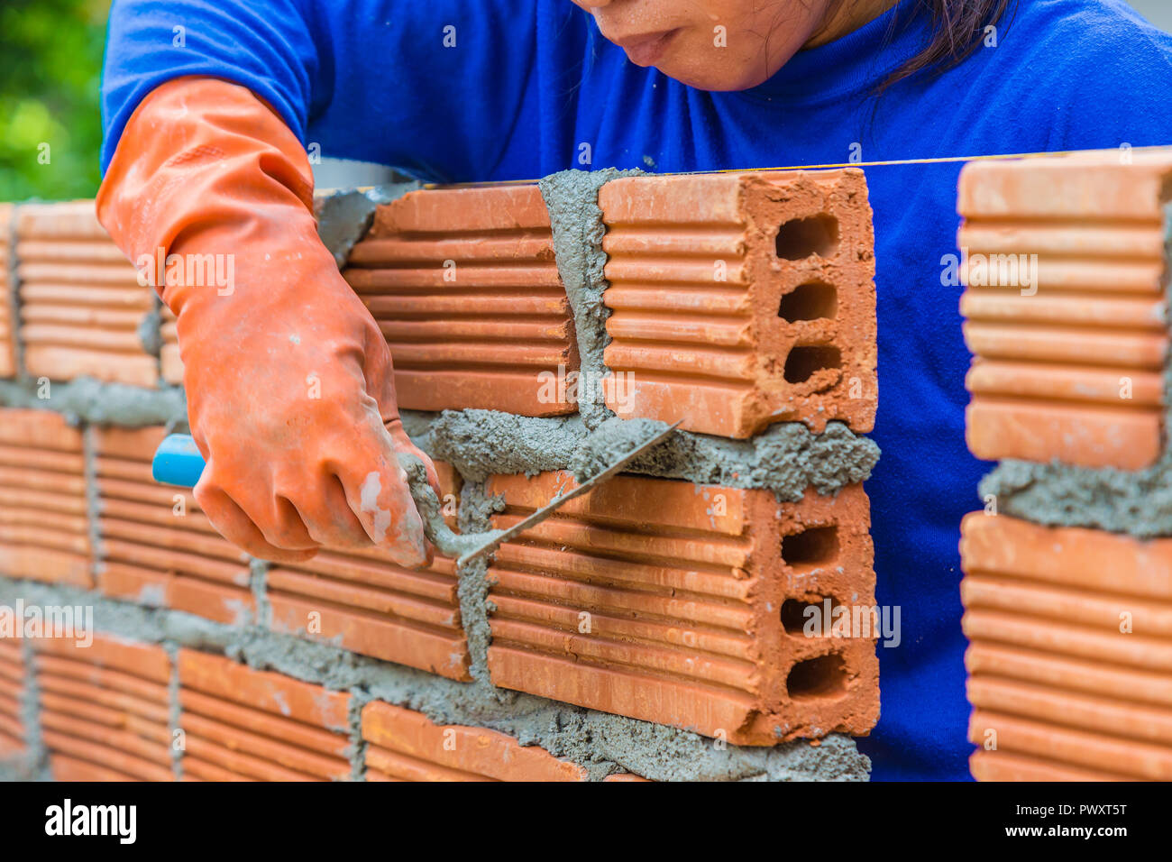 Female construction worker laying down brick wall one by one using ...