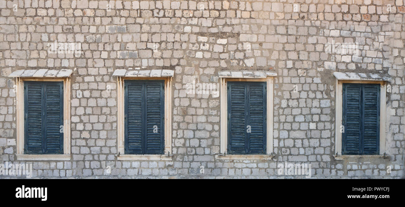 Four windows in old wall with closed blue shutters Stock Photo - Alamy