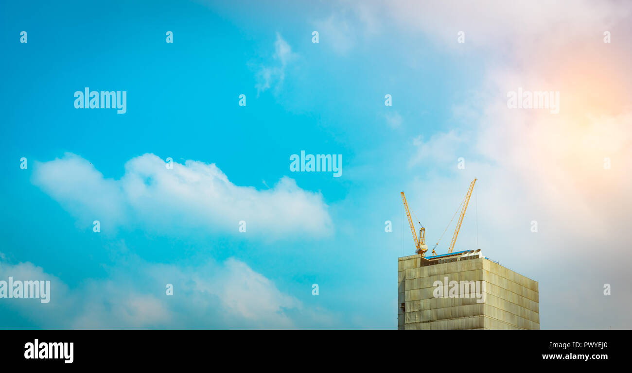 Construction crane on high-rise building with blue sky and white clouds ...