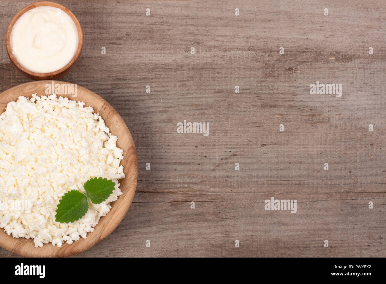 Cottage cheese in a wooden bowl with sour cream on old wooden ...