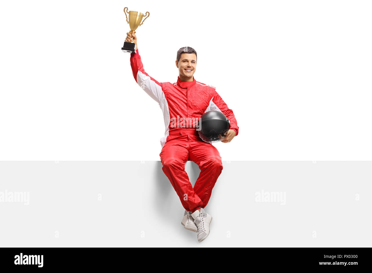 Winner racer in a suit holding a gold trophy cup and sitting on a panel ...