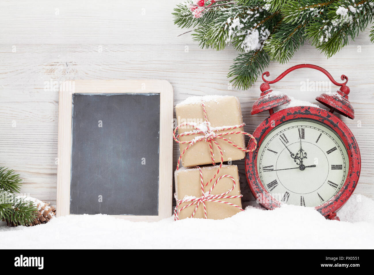 Christmas gift box, alarm clock and fir tree branch covered by snow in ...