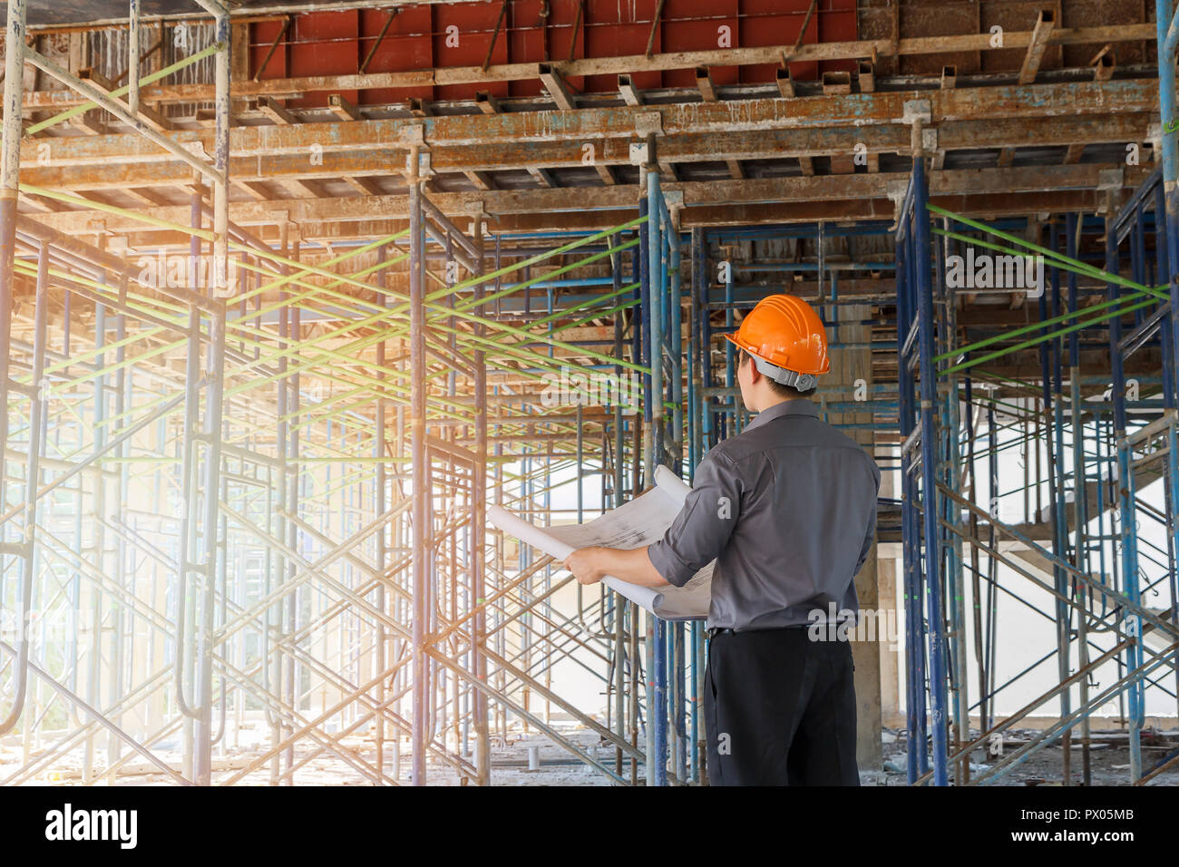 Engineer with blueprint in building construction site Stock Photo - Alamy