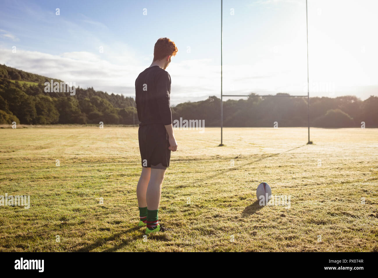 Rugby player standing with rugby ball in the field Stock Photo - Alamy