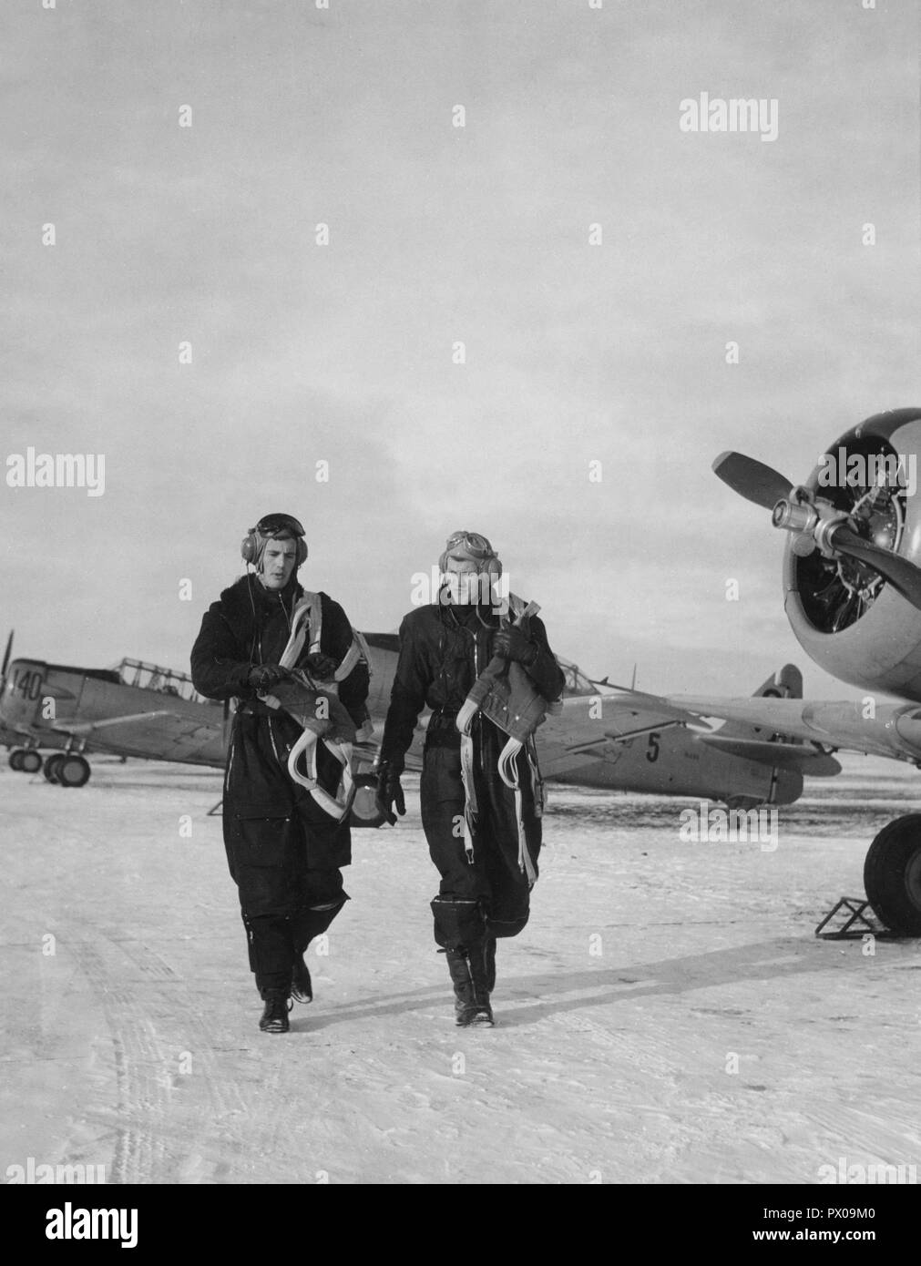 Pilots in the 1950s. Two pilots are walking past fighter aircraft a ...