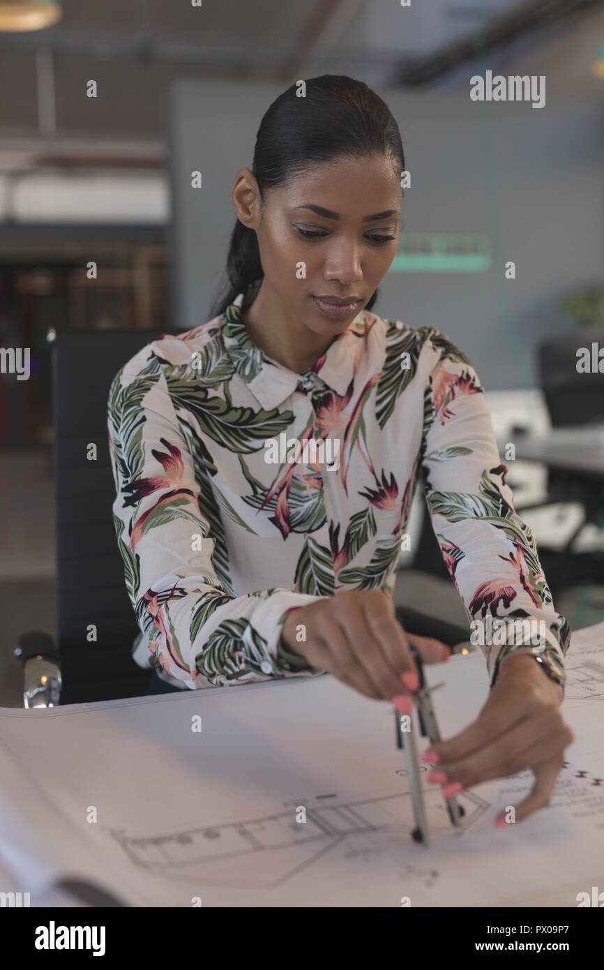 Female executive drawing on blueprint at desk Stock Photo - Alamy