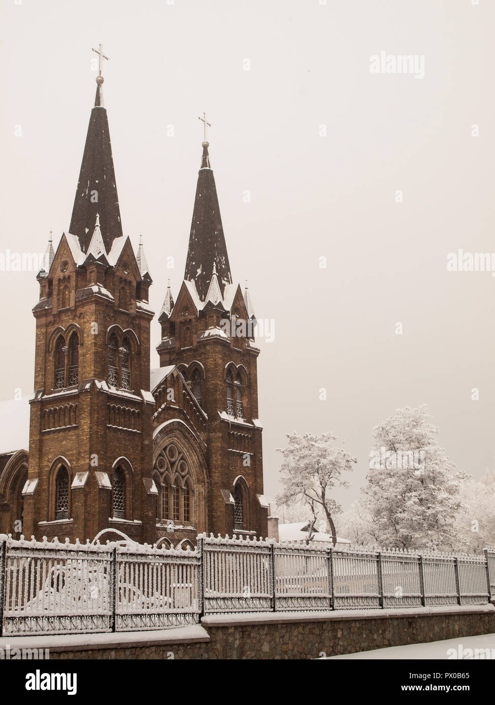 Roman catholic church with iron fence and trees covered with snow in ...
