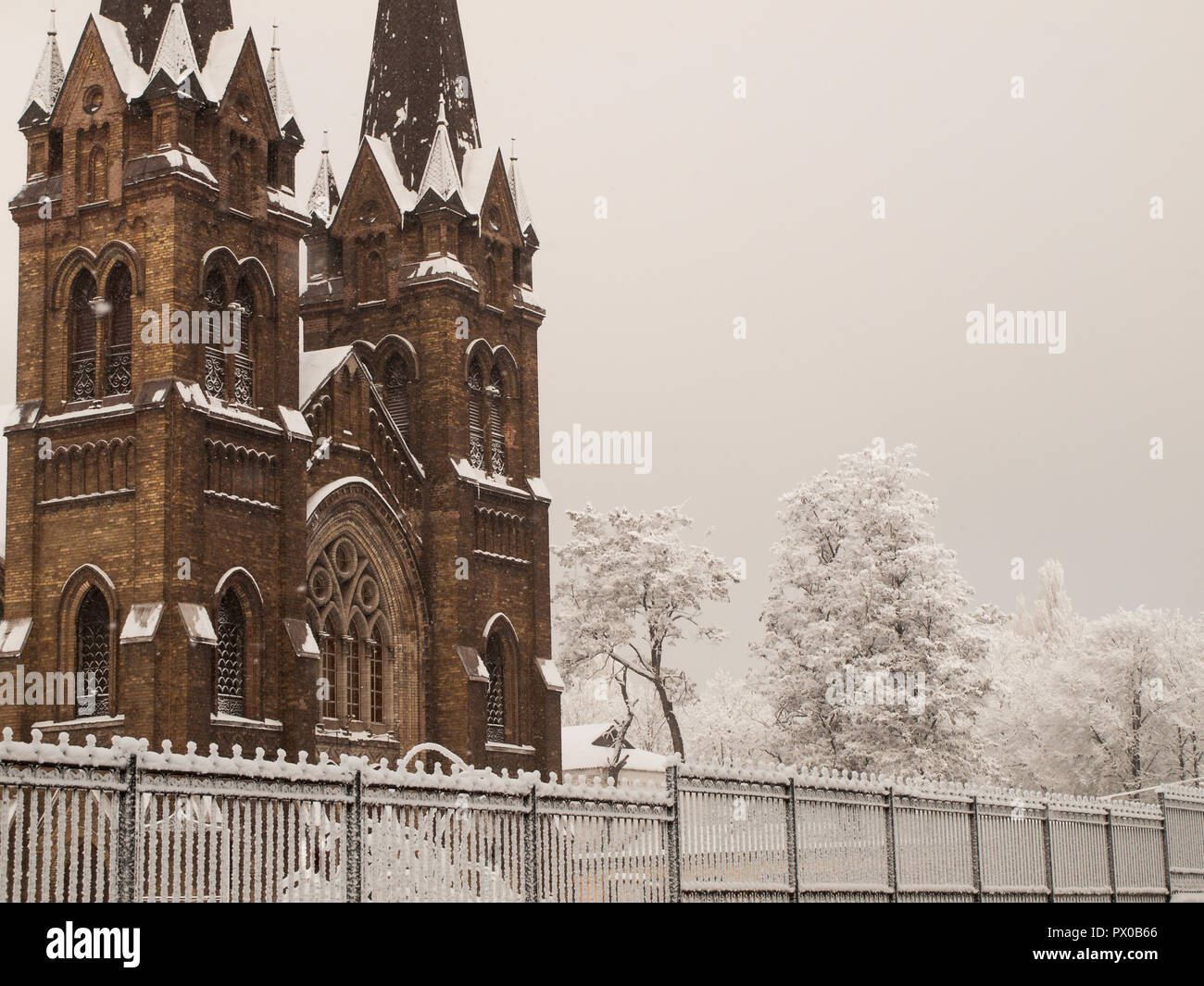 Roman catholic church with iron fence and trees covered with snow in ...