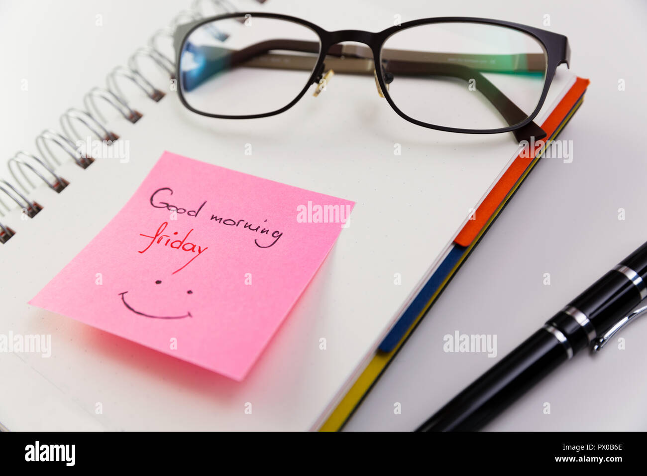 Good morning Friday, written on a post it glued to a notepad with ...