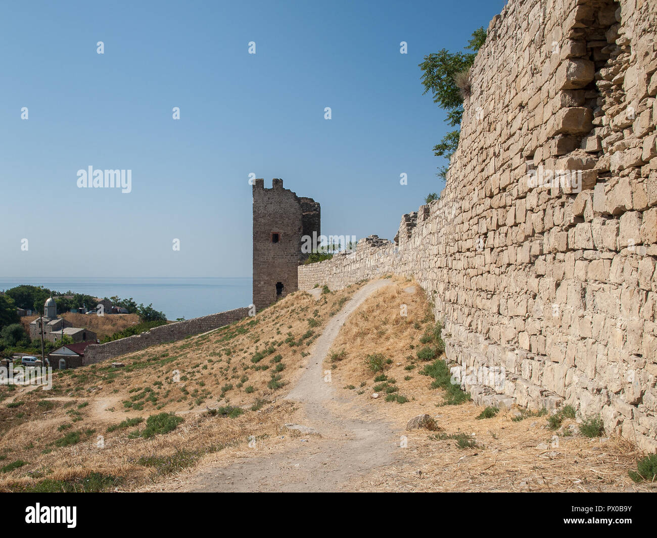 Stone tower of an ancient fortress with adjoining rocky walls with sea ...