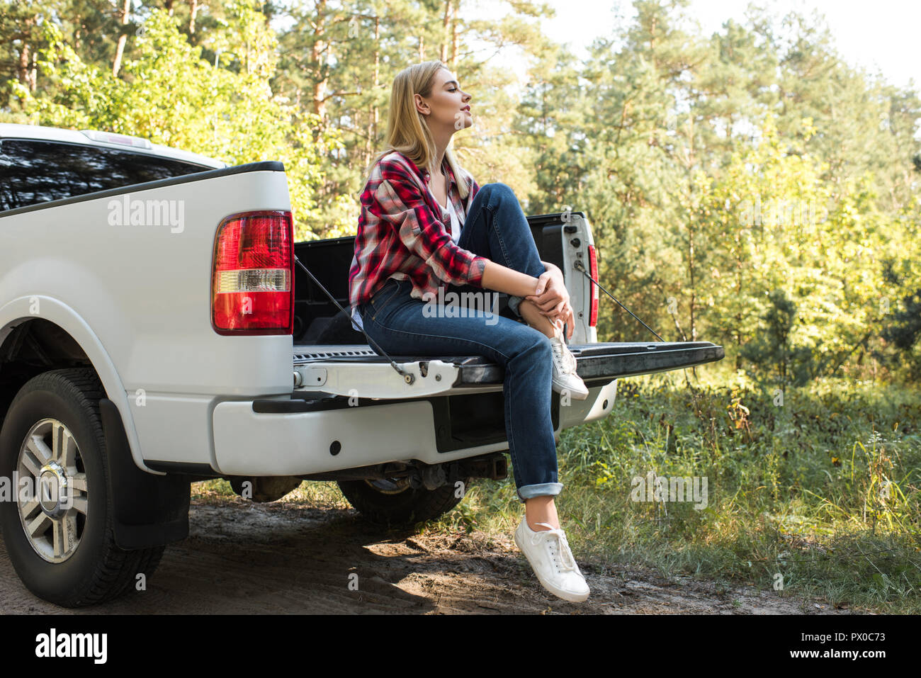 side view of young woman sitting in trunk of pick up car outdoors Stock ...