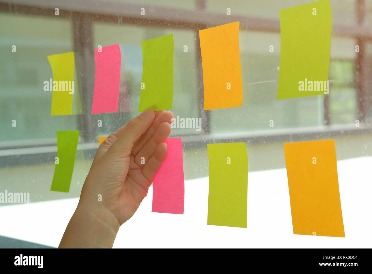 hand hold adhesive notes on glass wall at workplace. Sticky note paper ...