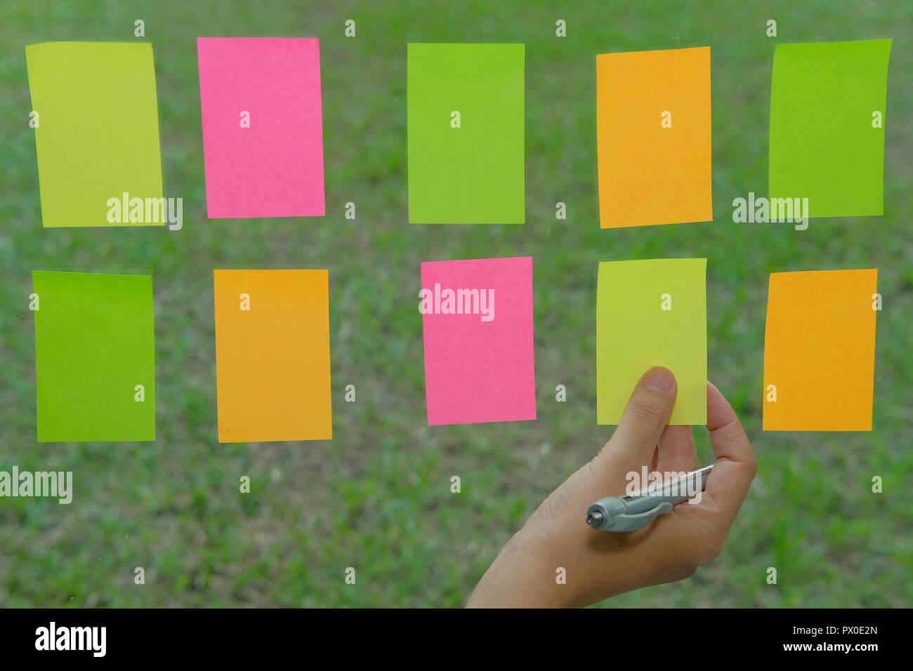 hand hold adhesive notes on glass wall at workplace. Sticky note paper ...