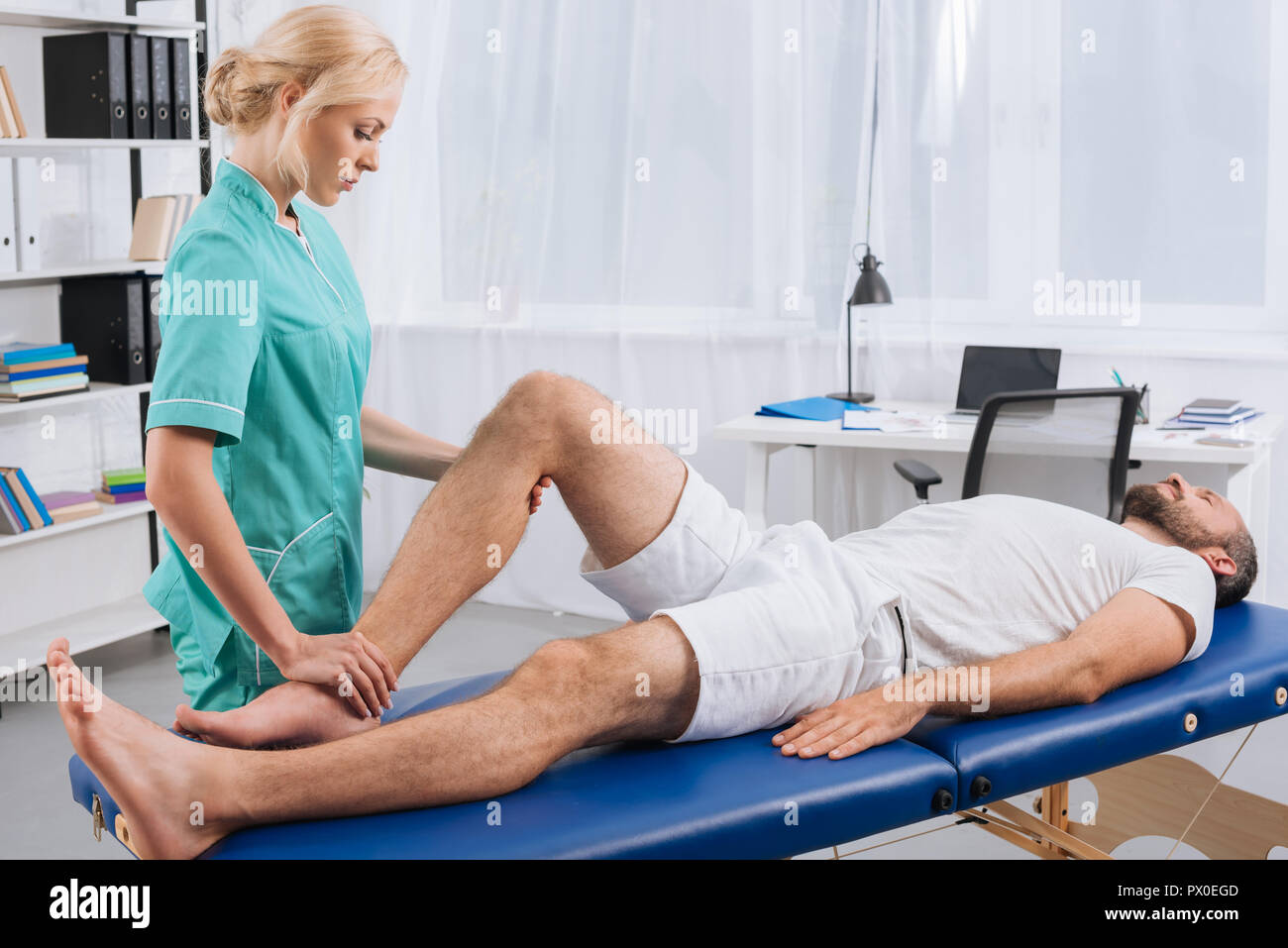 Female Massage Therapist Doing Leg Massage To Patient On Massage Table