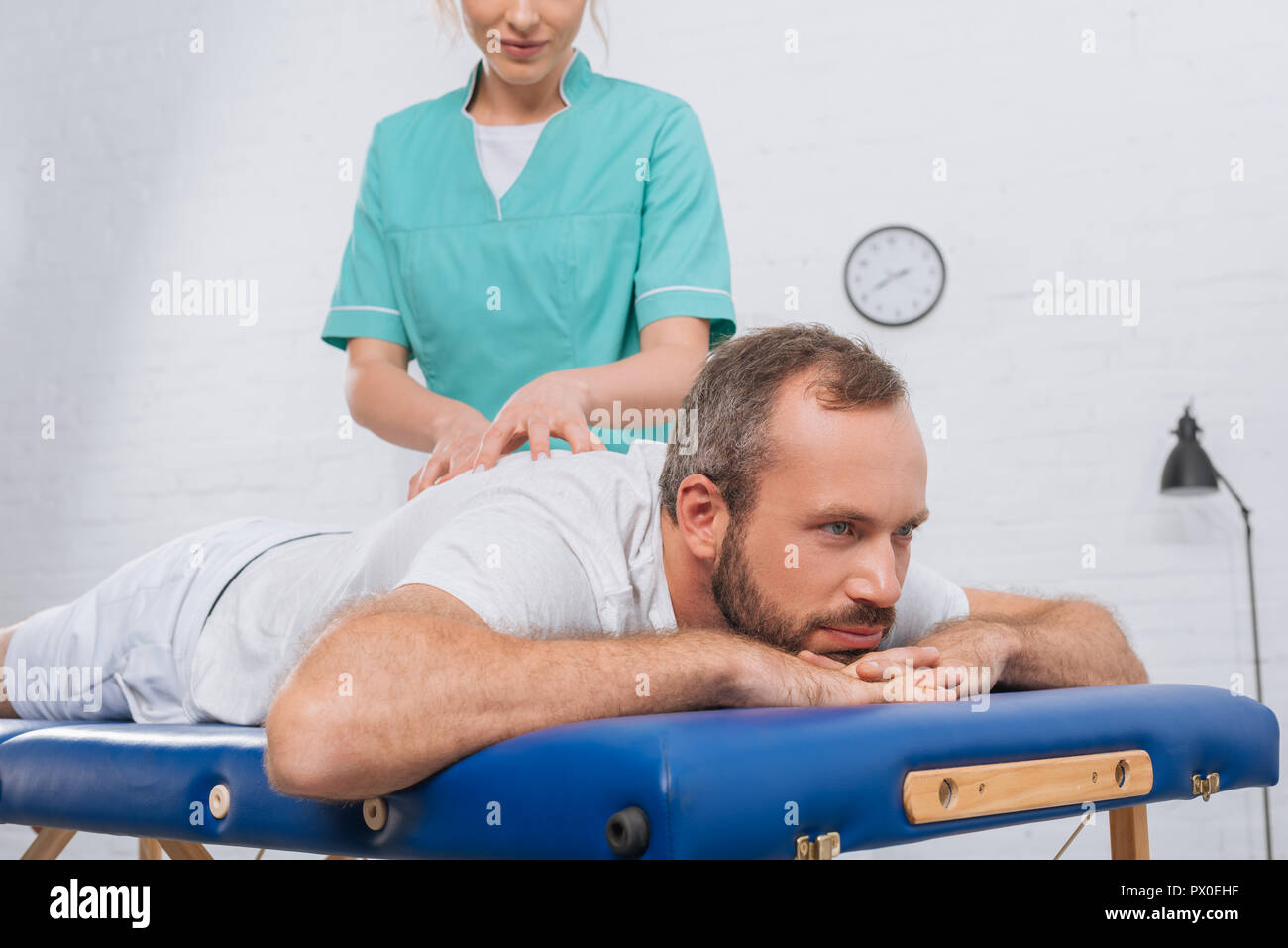 partial view of female massage therapist doing massage to patient on ...
