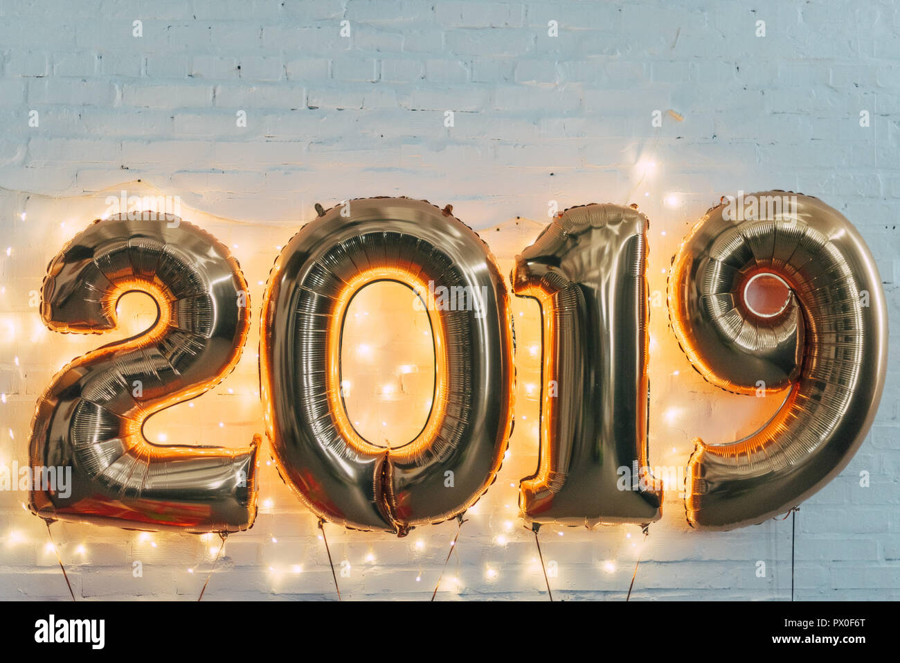 2019 golden balloons with light garland on white wall for new year ...
