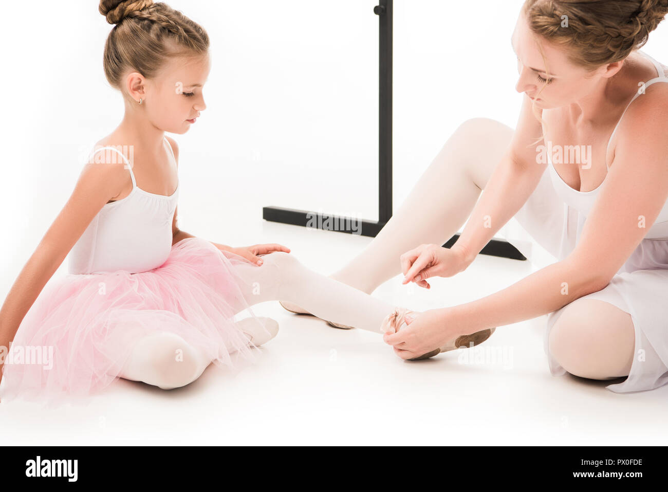 adult female trainer pointing at pointe shoes of little ballerina near ...
