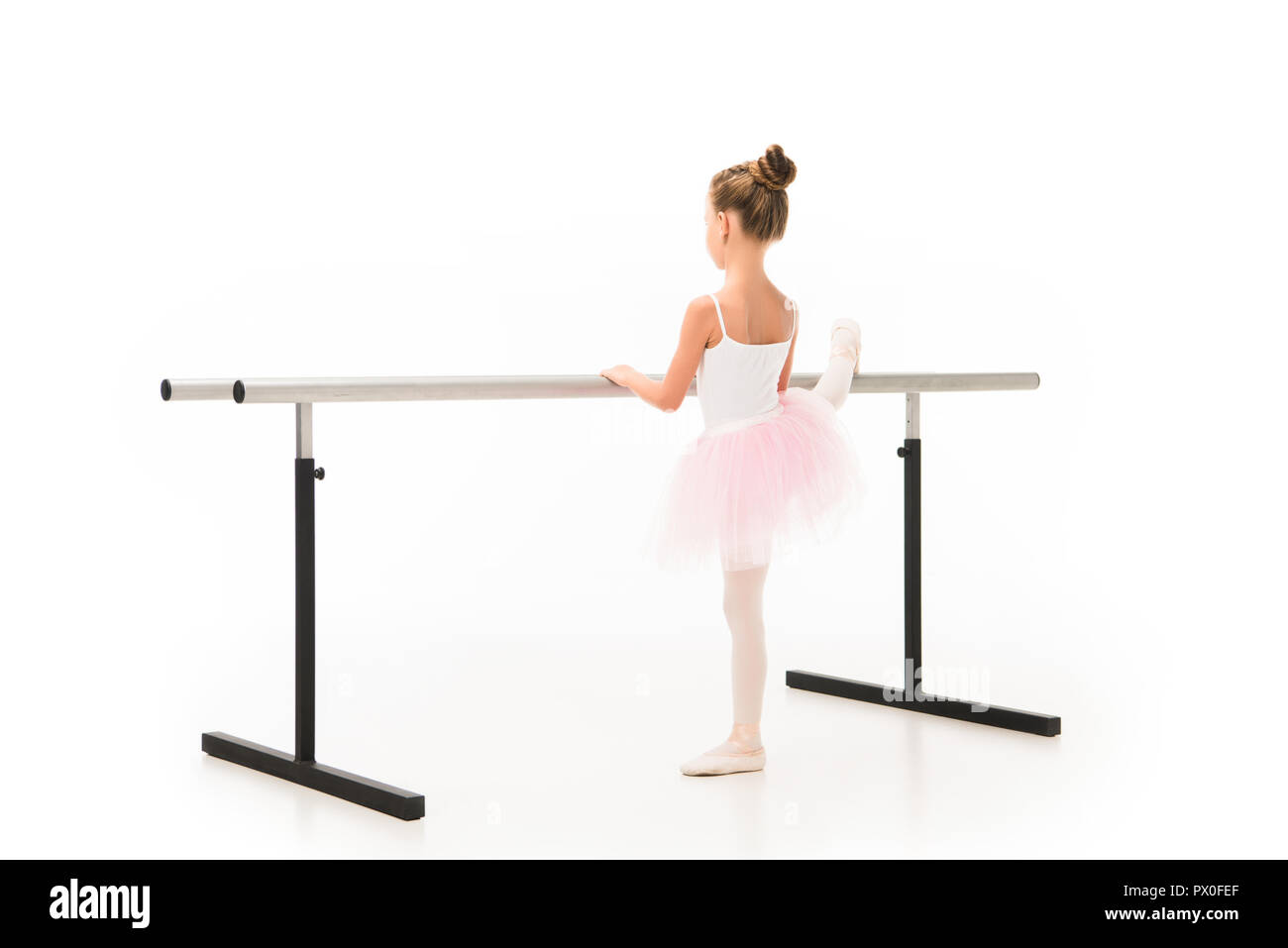 rear view of little ballerina in tutu and pointe shoes exercising at ...