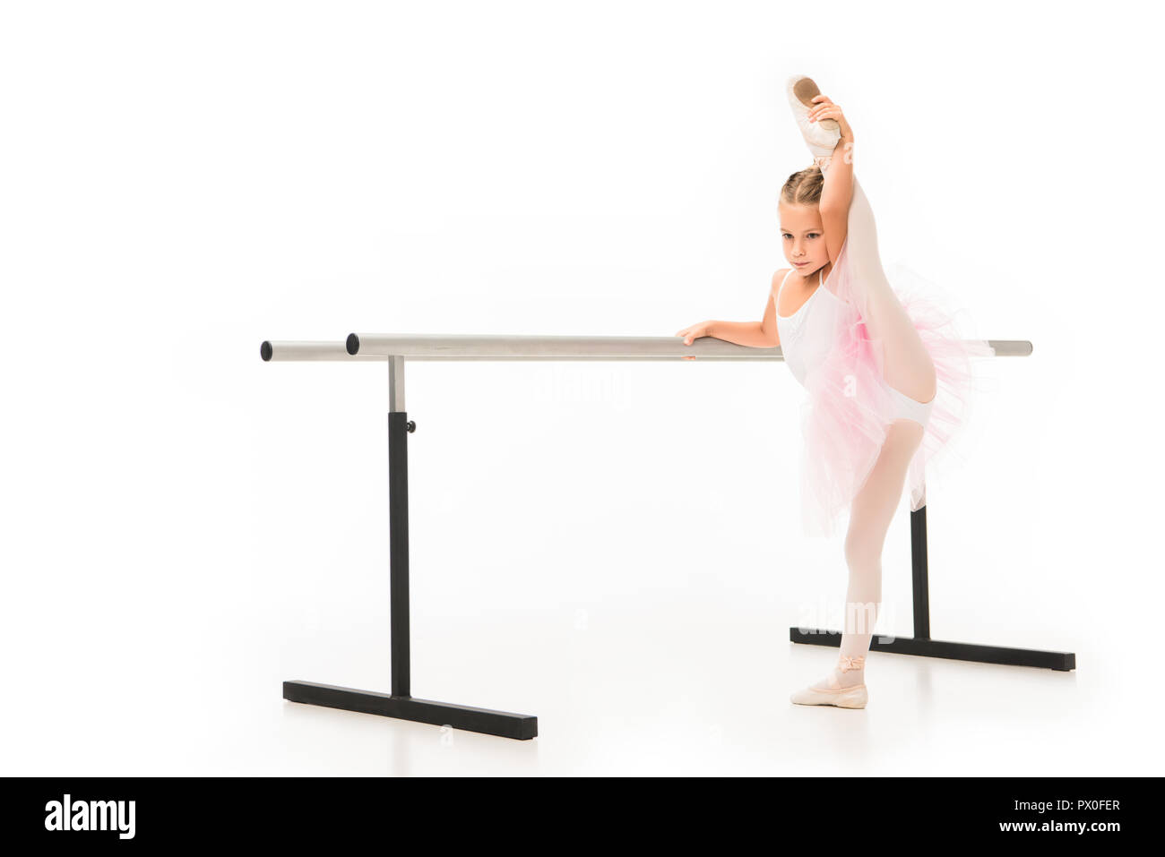 little ballerina in tutu stretching leg at ballet barre stand isolated ...