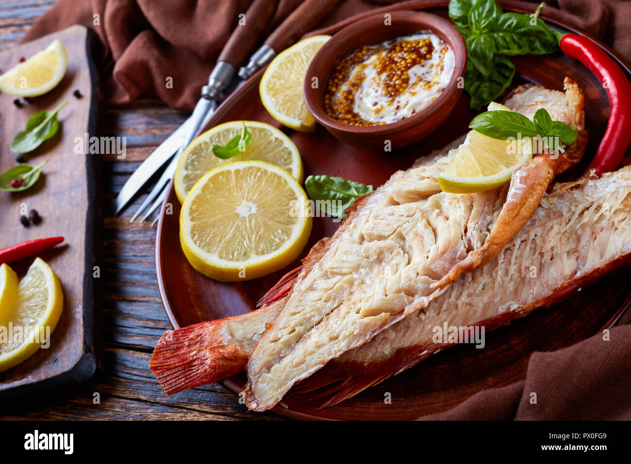 fillet of red snapper served on a earthenware plate with fresh basil ...