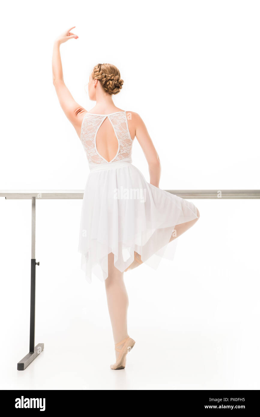 rear view of ballerina in tutu and pointe shoes practicing at ballet ...