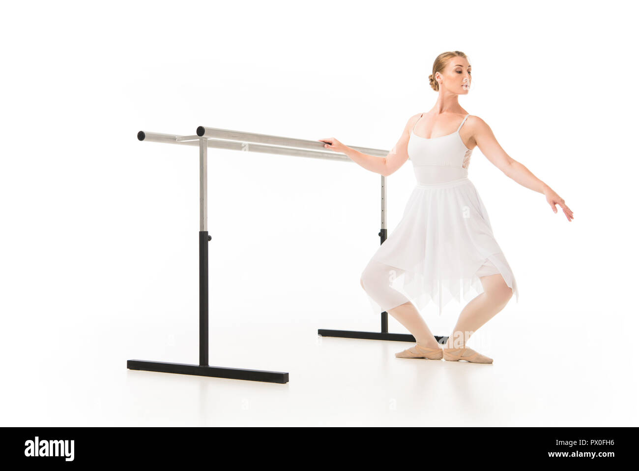 elegant ballerina in tutu and pointe shoes practicing at ballet barre ...