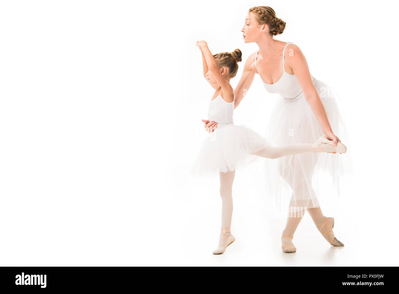 side view of adult female trainer in tutu helping little ballerina ...