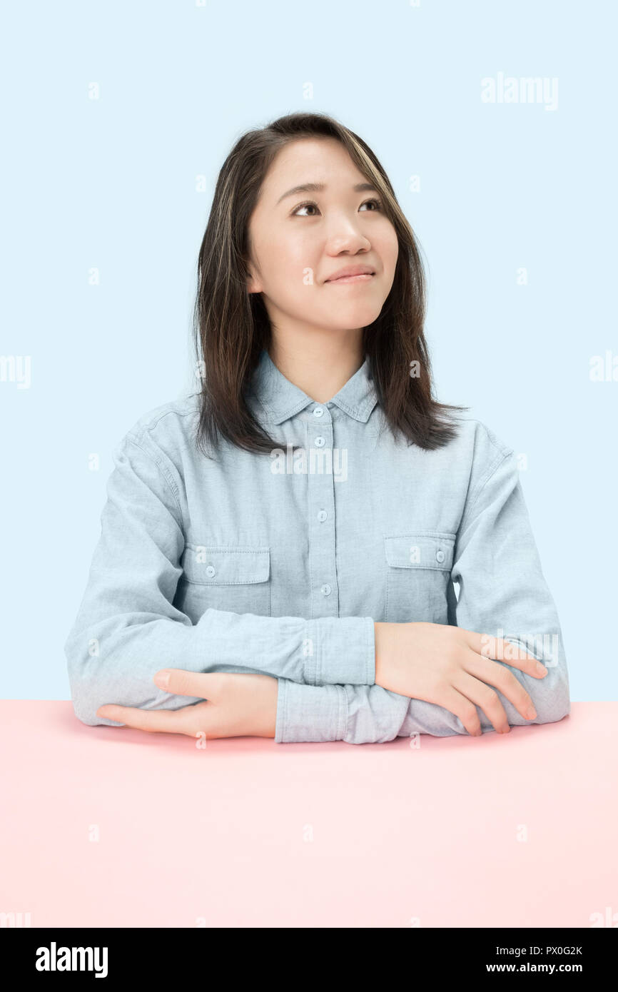 Serious business woman sitting at table, looking up isolated on trendy ...