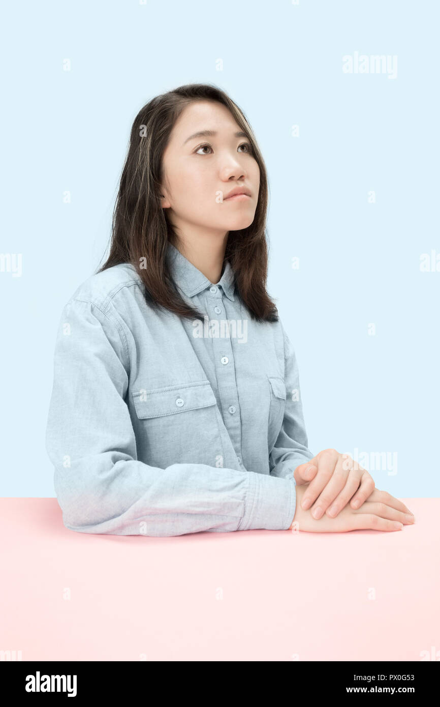 Serious business woman sitting at table, looking up isolated on trendy ...