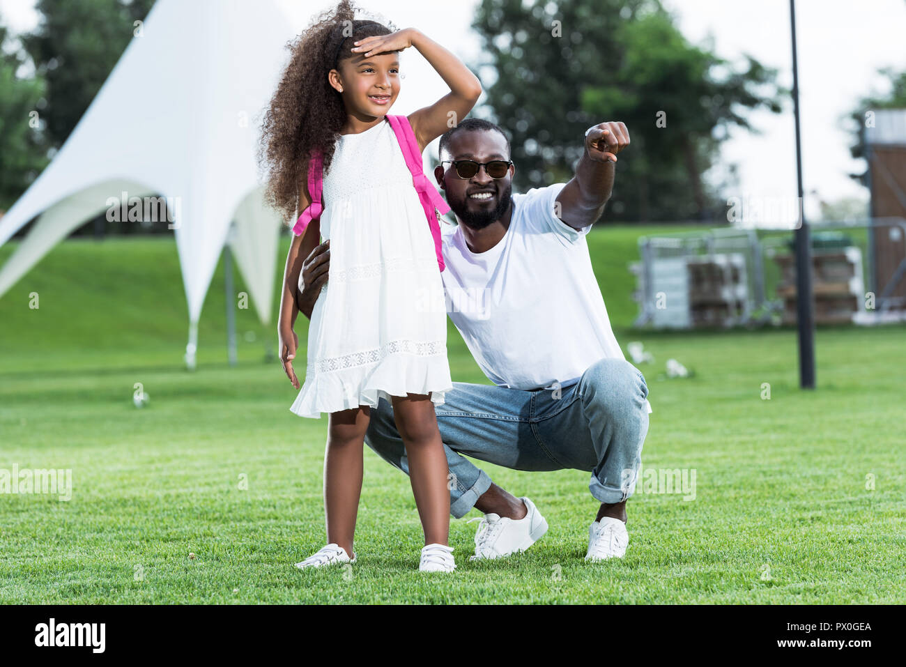 smiling african american father pointing on something to daughter with ...