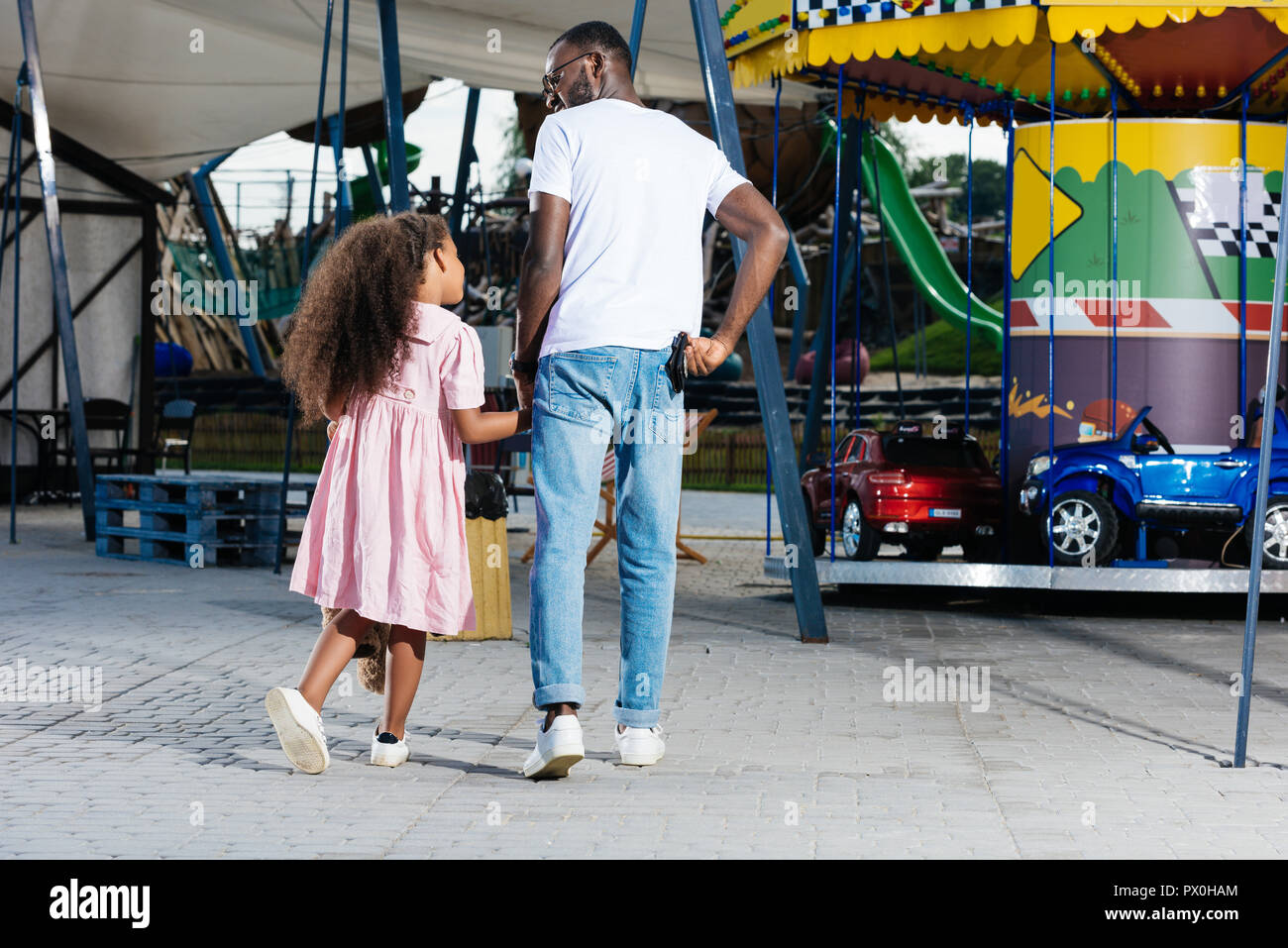 back view of african american police officer walking with daughter and ...