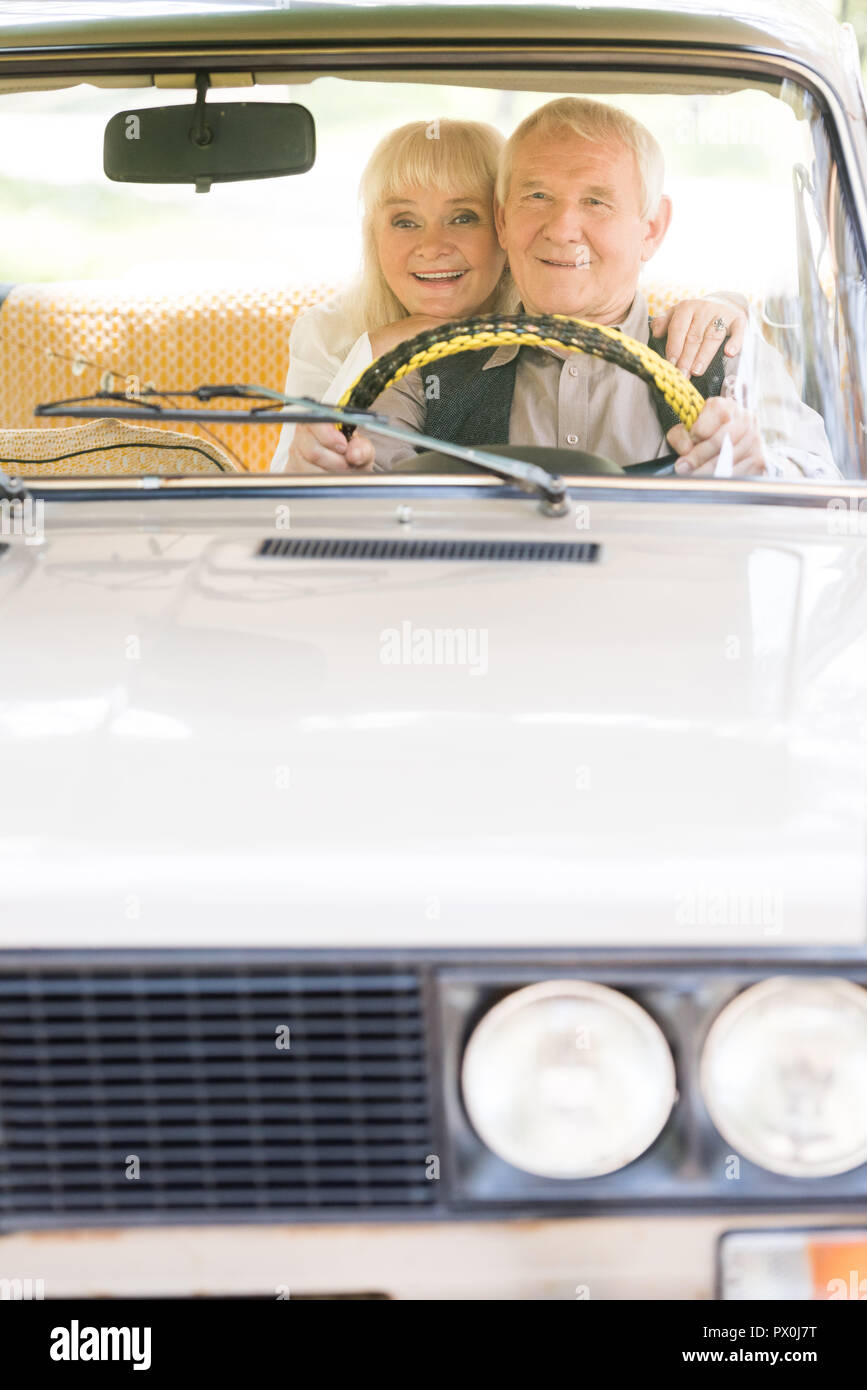 happy senior wife hugging husband while he driving vintage car Stock ...
