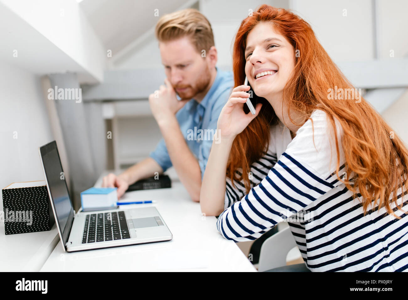 Beautiful ginger woman working in office with colleague Stock Photo - Alamy