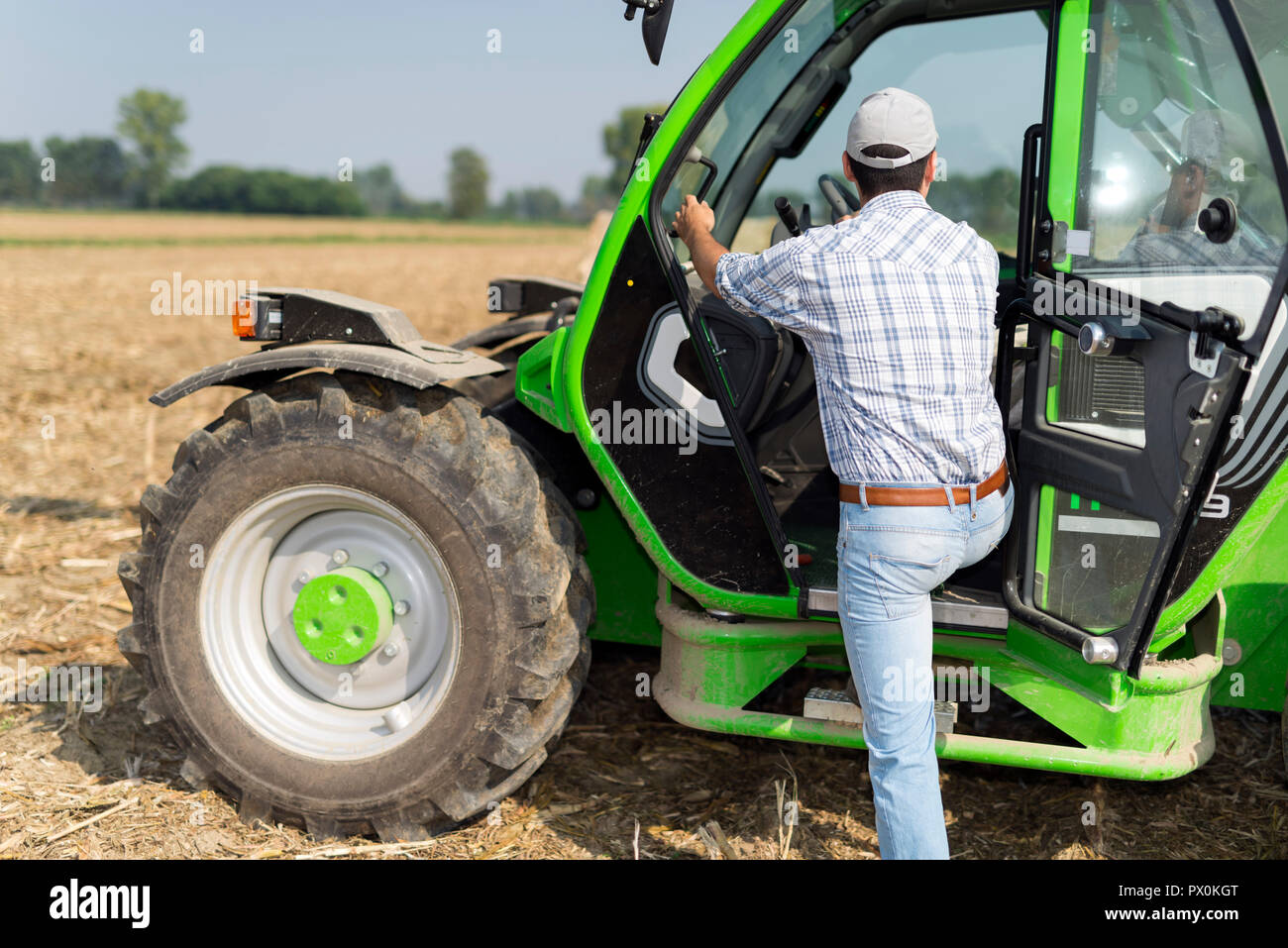 Farmer getting in his tractor Stock Photo - Alamy