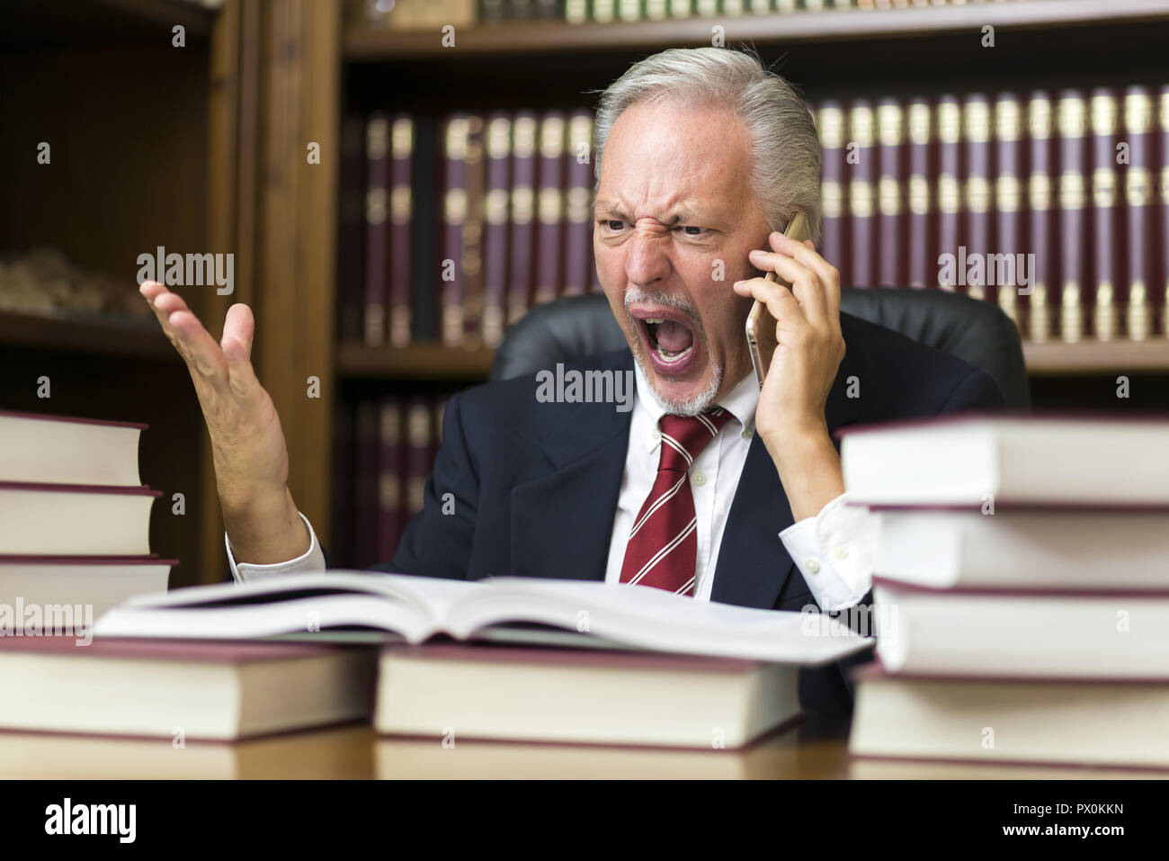 Angry businessman yelling on the cellphone while reading a book Stock ...