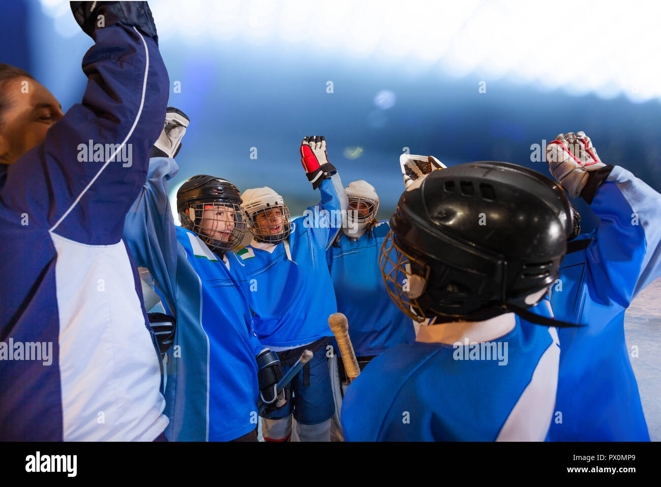 Coach and hockey players doing team cheer on rink Stock Photo - Alamy