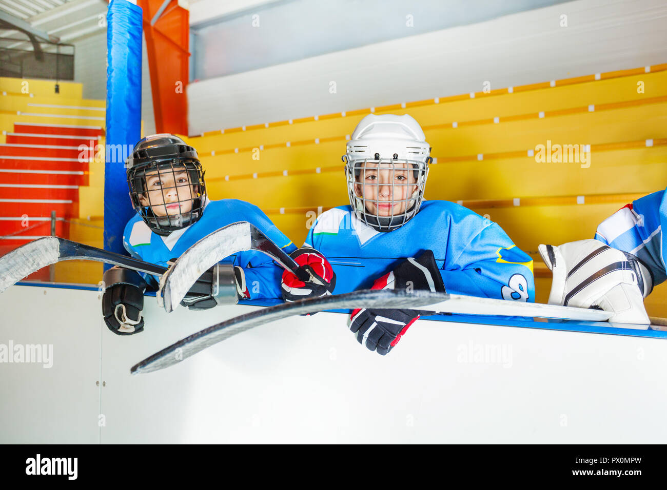 Young hockey players sitting on bench at stadium Stock Photo - Alamy