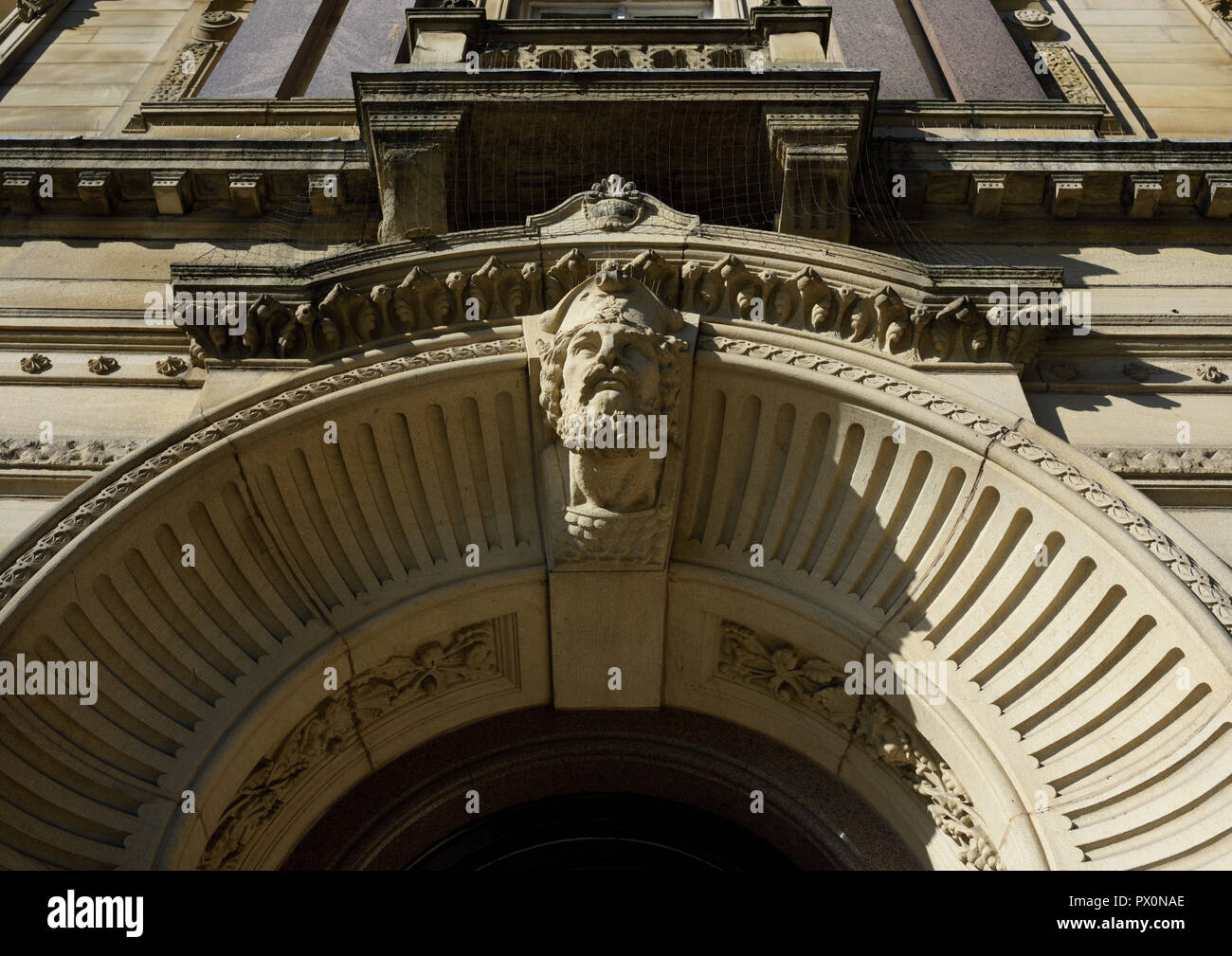 Ribbed stone arch with grotesque head of plutus keystone in old bank ...