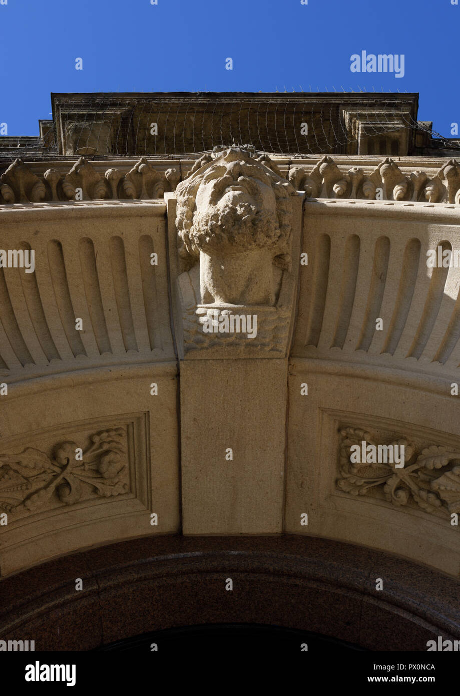 Ribbed stone arch with grotesque head of plutus keystone in old bank ...