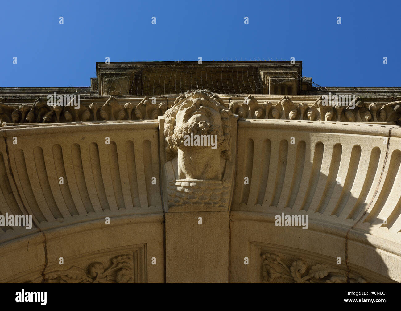 Ribbed stone arch with grotesque head of plutus keystone in old bank ...