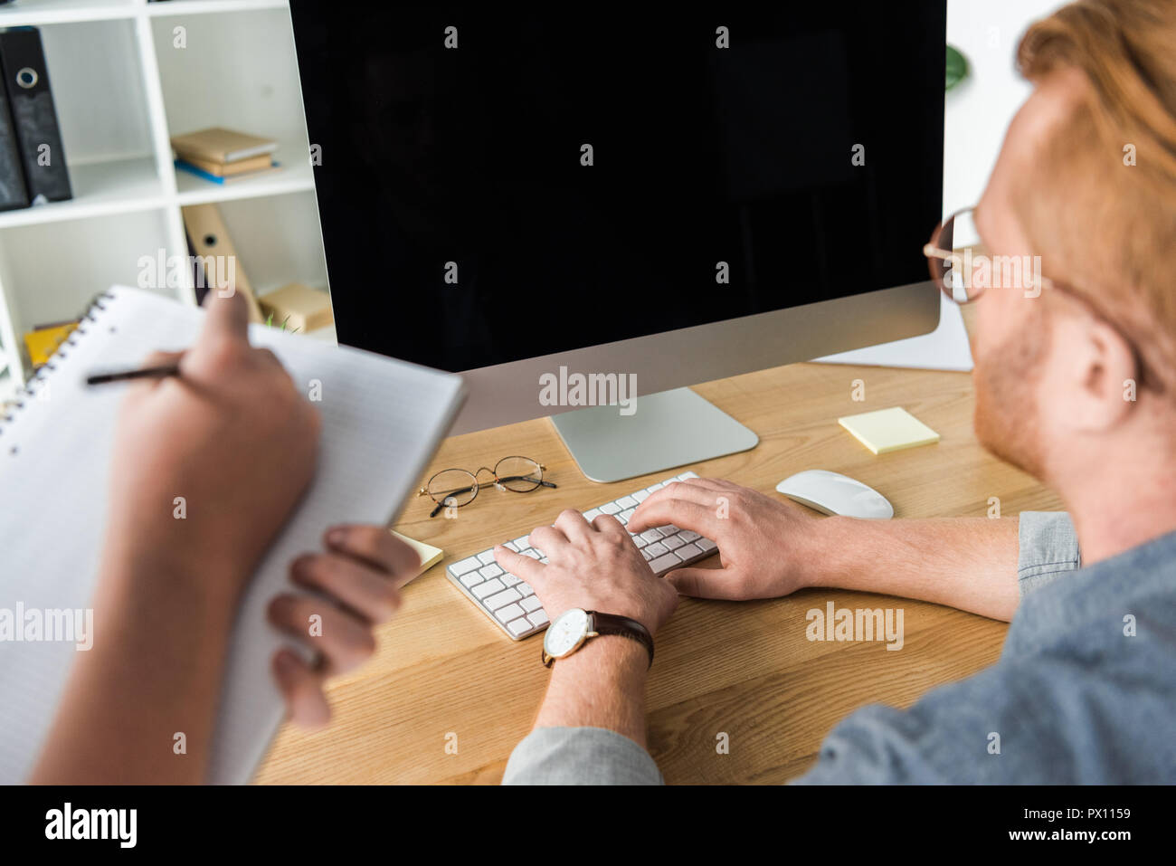 cropped image of father using computer, son holding pen and notebook at ...