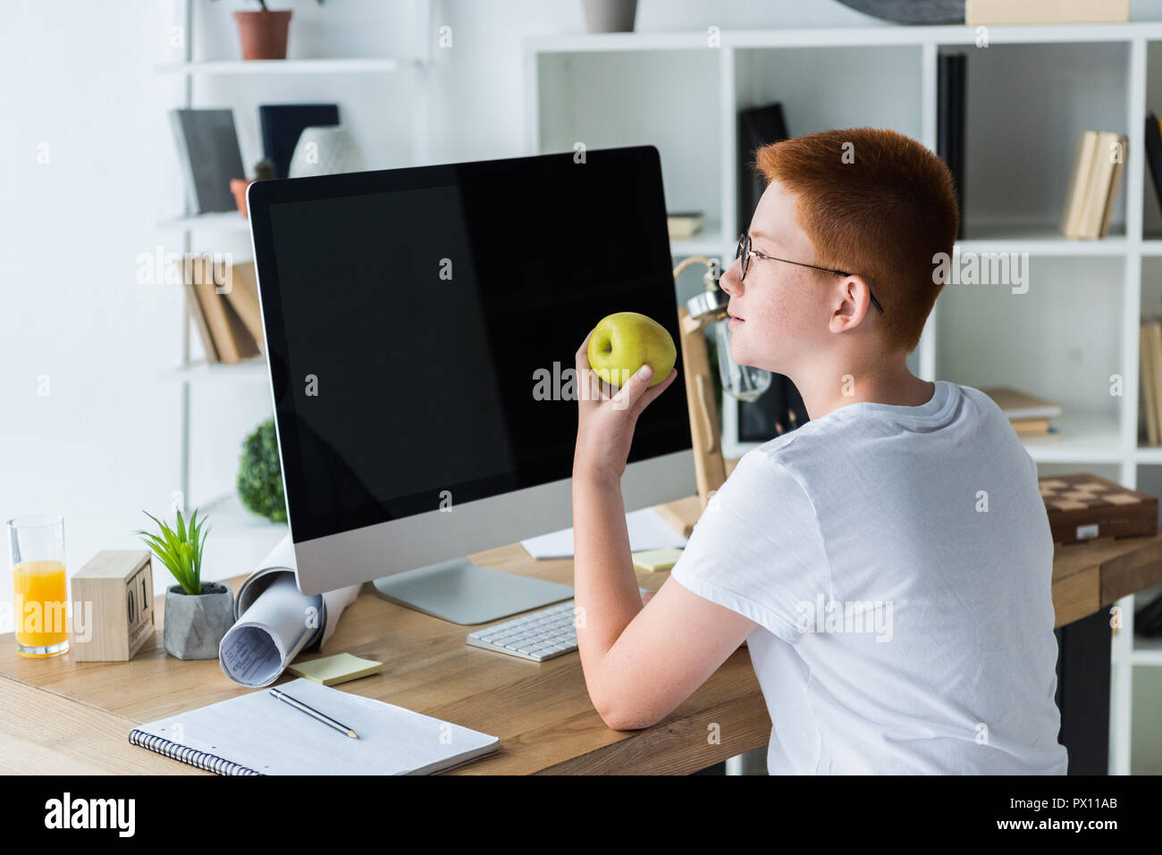 preteen ginger hair boy holding apple near computer at home Stock Photo ...