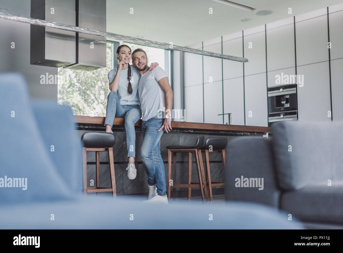 selective focus of attractive woman sitting on kitchen counter and ...